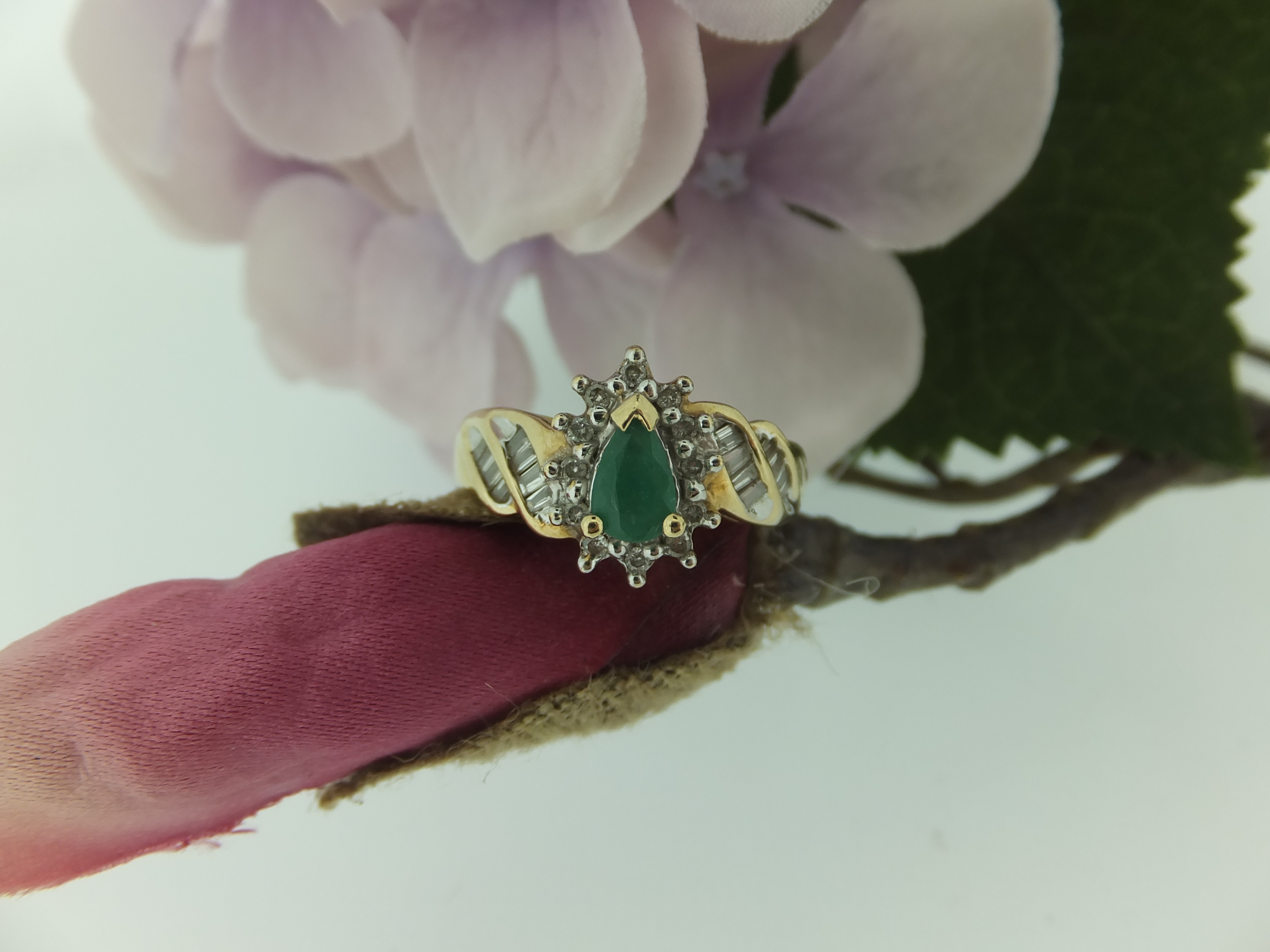 A yellow gold ring featuring emerald and diamonds